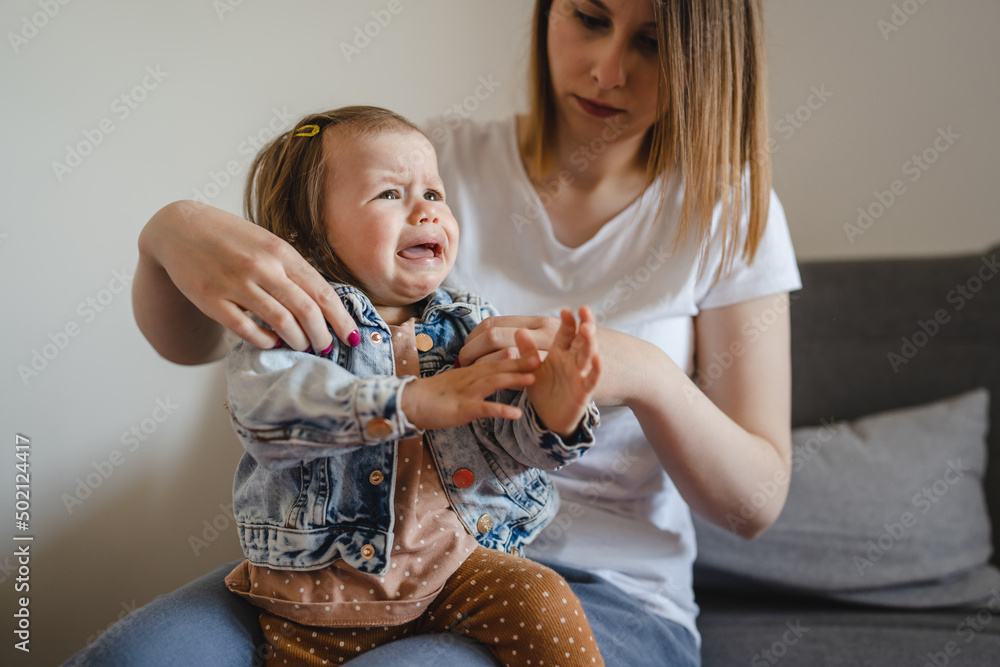 Small caucasian baby girl infant child with her mother dressing ...
