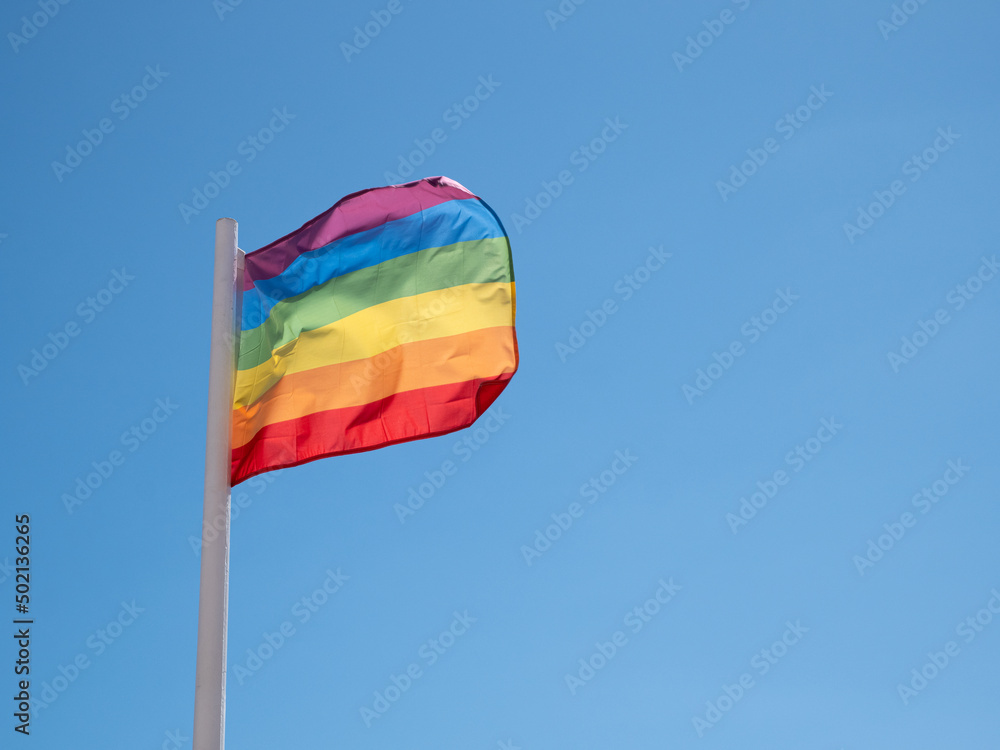 Rainbow flag blue sky background. LGBTQ community flag. Stock Photo ...
