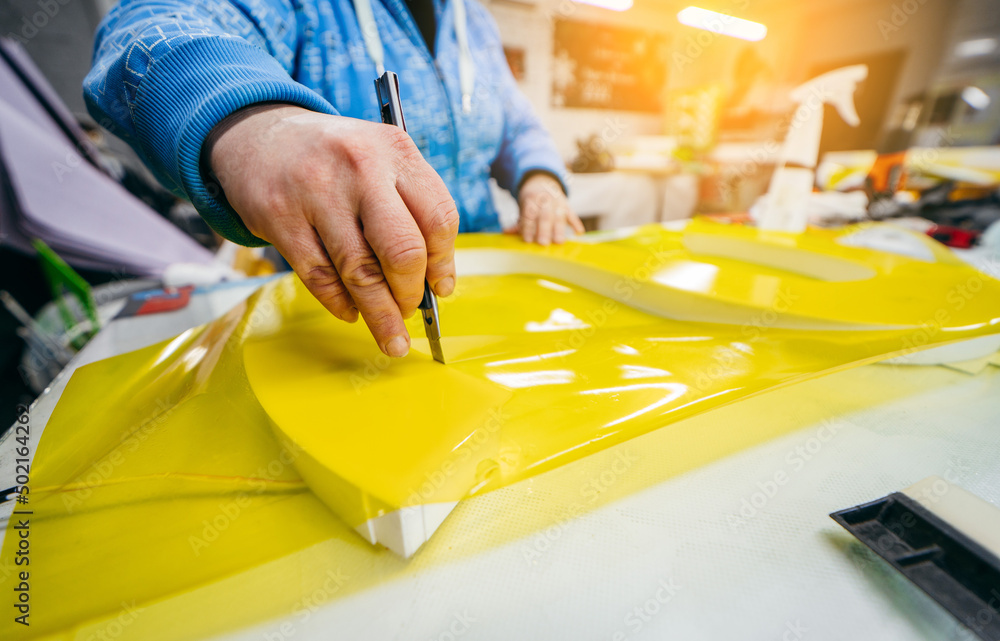 Applying colored yellow membrane to a surface of plastic 3d letter of ...