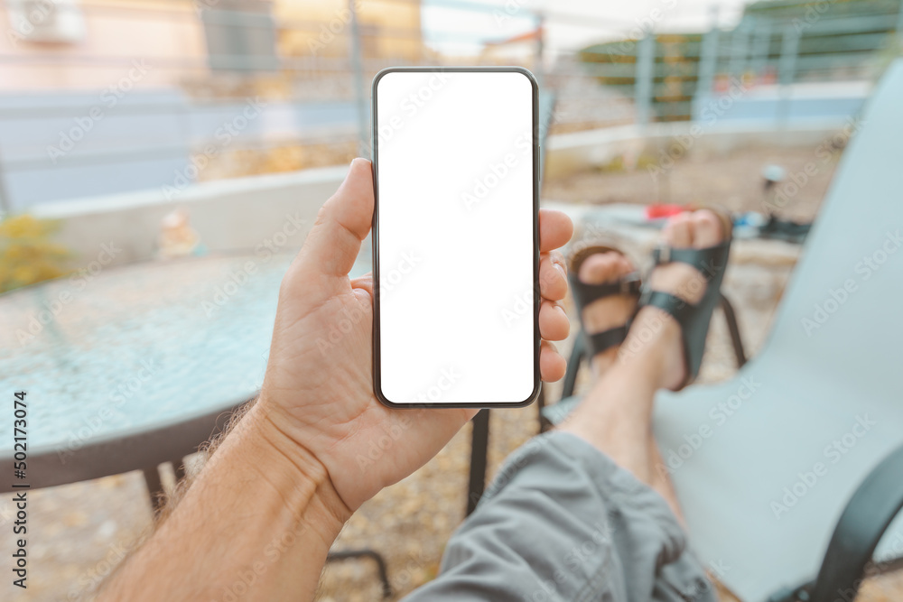 Man sitting on apartment terrace with feet on the table looking at ...