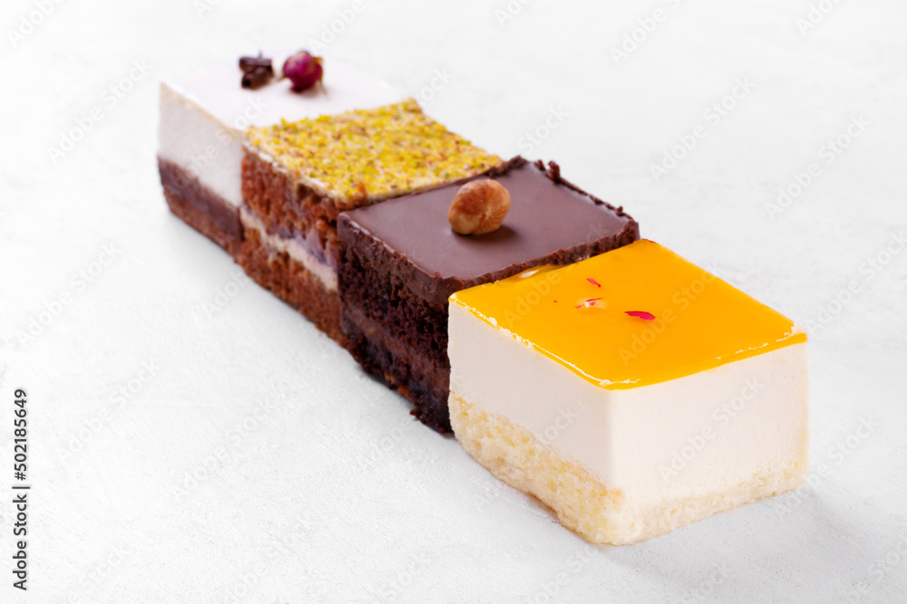 Four assorted cakes on the white table. Mousse cake with passion fruit ...
