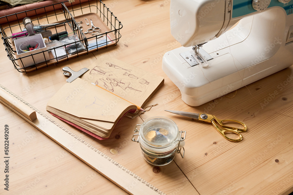 Part of wooden table with electric sewing machine, ruler, scissors ...