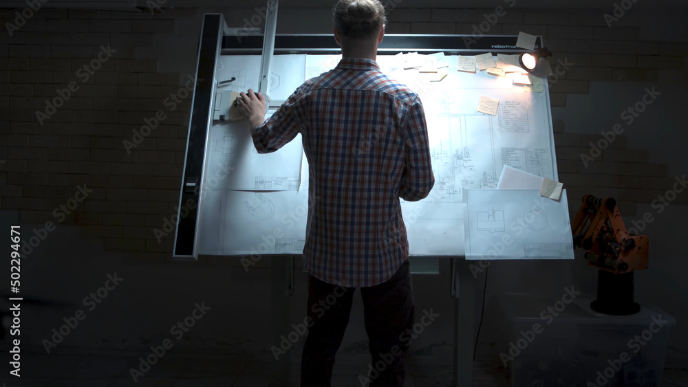 Young engineer standing at the white board with drawing and plan back ...