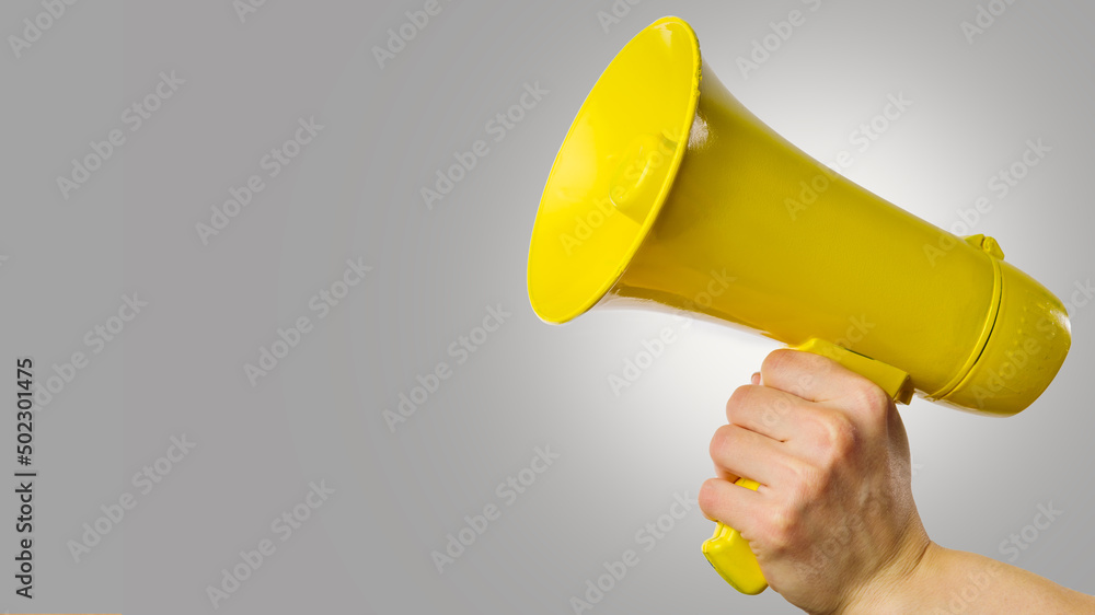 Yellow megaphone in a man's hand on a white background. The concept is ...
