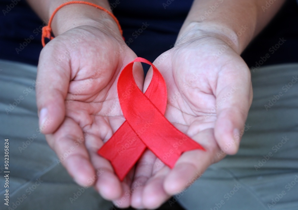 Man's hand is holding red ribbon with blurred background,that's symbol ...