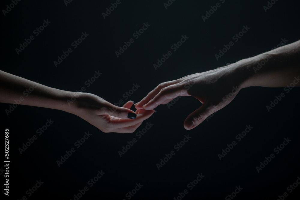 Two hands stretch each other, black background. Couple in love holding ...