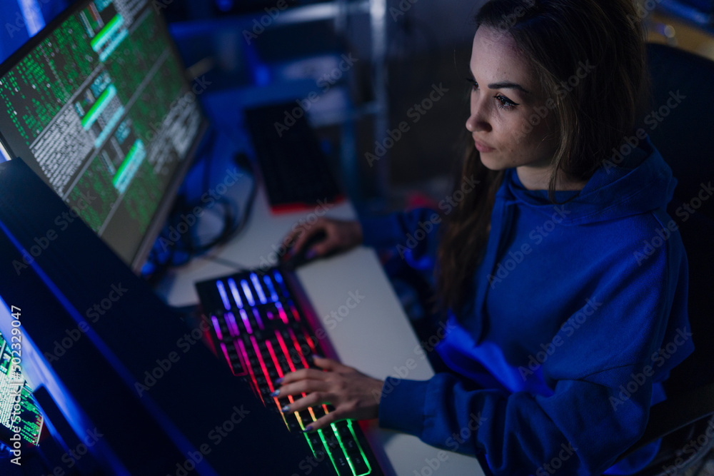 Young woman hacker by computer in the dark room at night, cyberwar ...