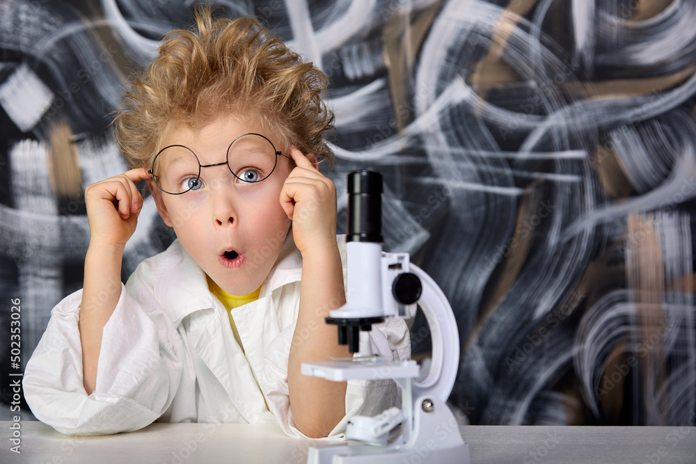 Stockfoto Blond boy bulged his eyes in surprise and raised glasses ...