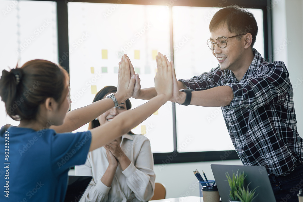 The concept of unity and teamwork. Young people in the high five office ...