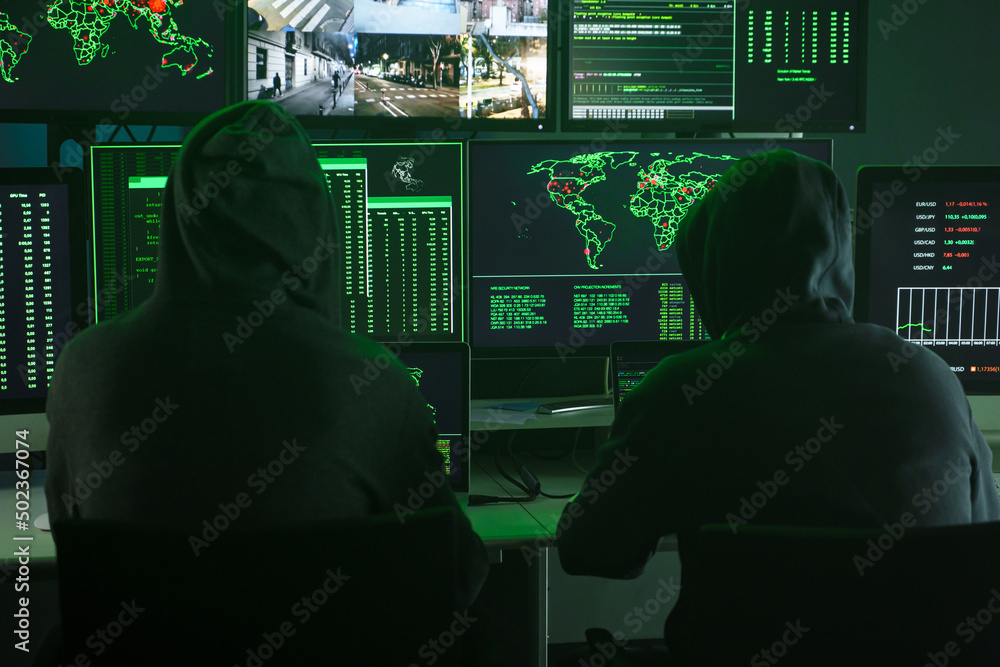 Team of Computer hackers coding on keyboard hidden in illegal hideout ...