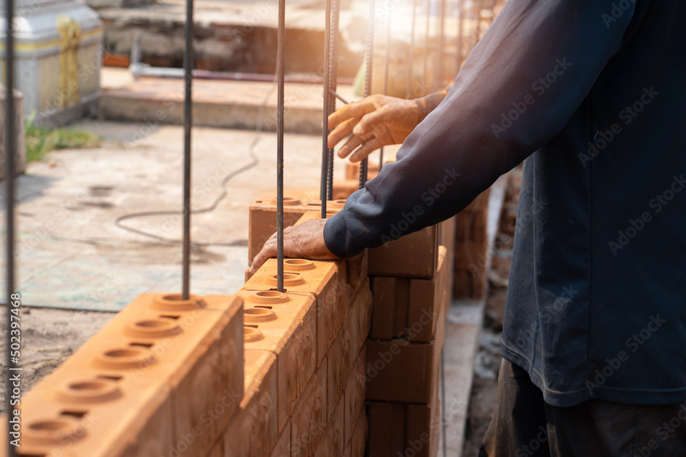 Builder carefully puts red brick on the masonry. Quick work bricklayer ...