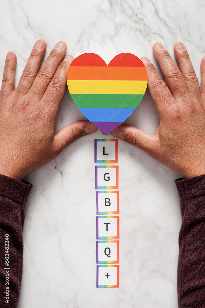 Hands of a mature man placing a heart with the colors of the movement ...