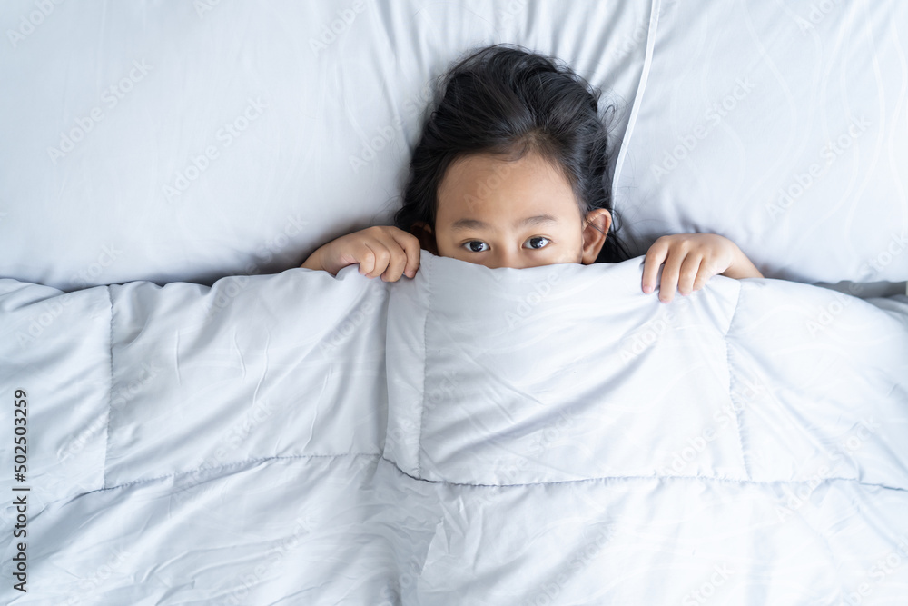 Top view cute asian child little girl watching from her bed under the ...