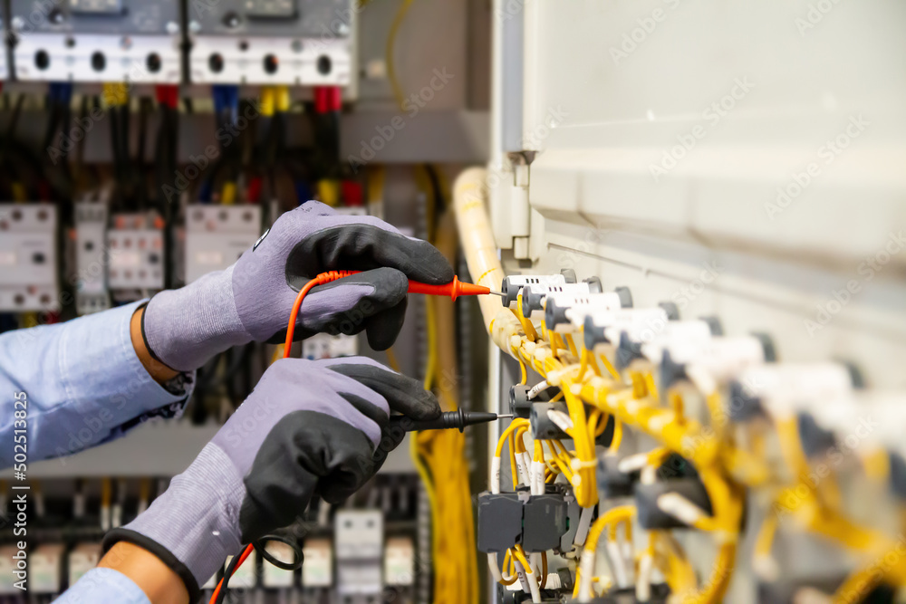 Electrical engineer using digital multi-meter measuring equipment to ...