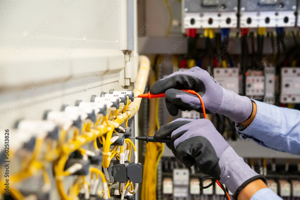 Electrical engineer using digital multi-meter measuring equipment to ...