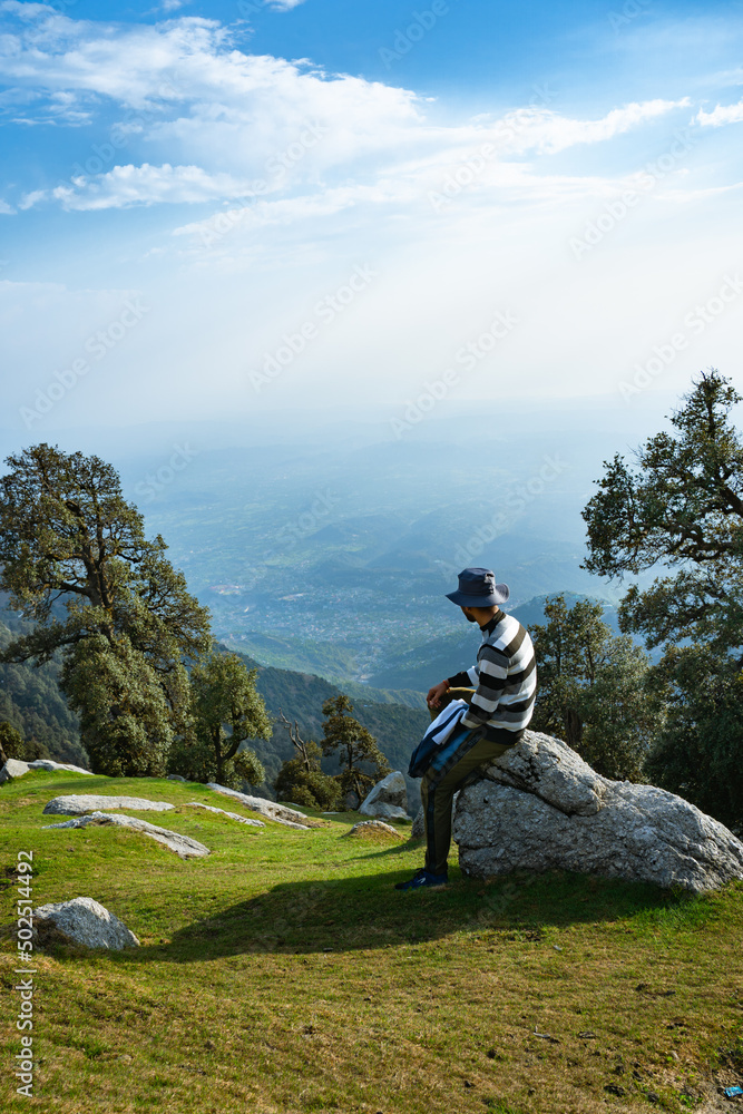 Moment of loneliness. Man sit on the peak of rock and watching into ...