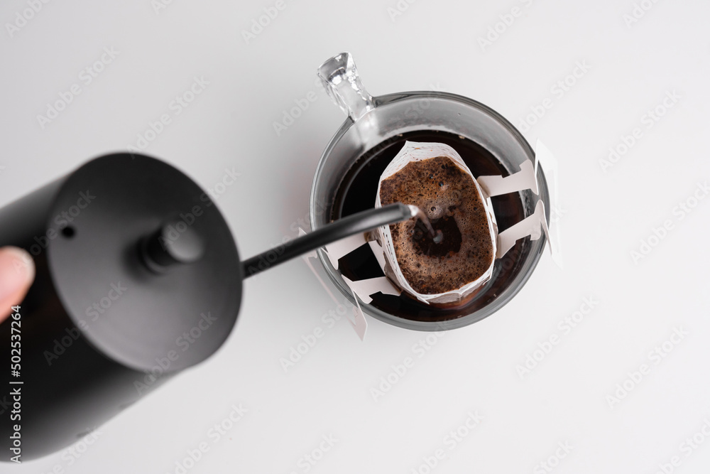 Black steel long spout drop kettle pouring hot water into a drip coffee ...