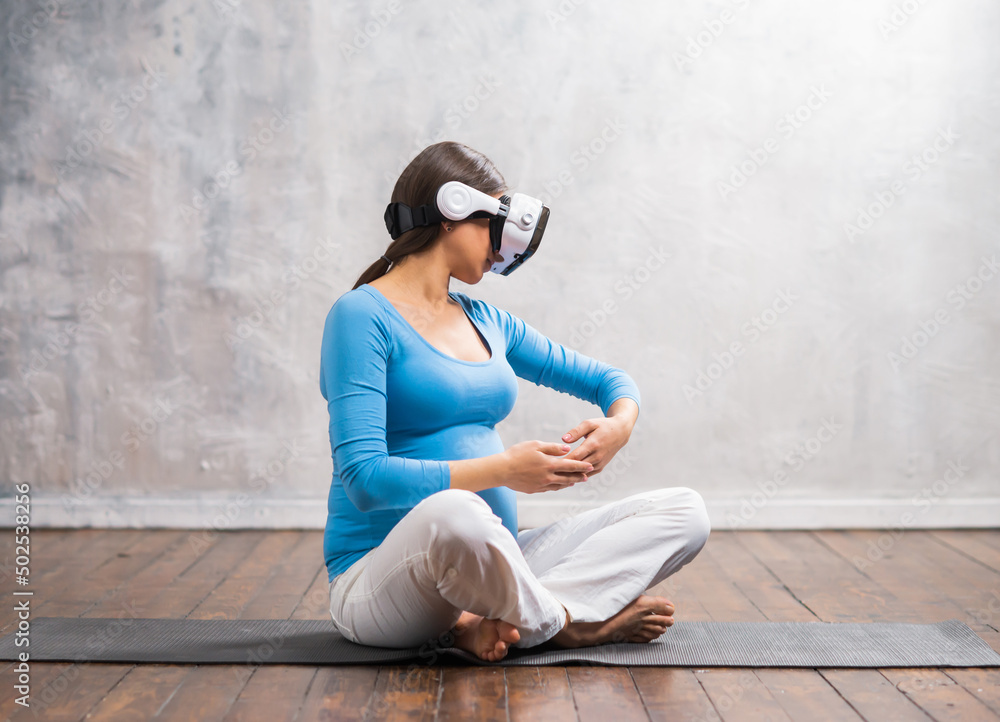 Young pregnant woman in VR helmet. She is preparing for the birth of a ...