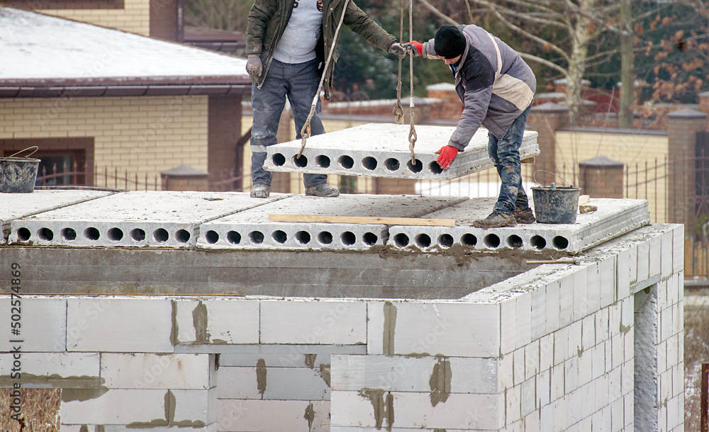 Builder worker installing concrete floor slab panel at building ...