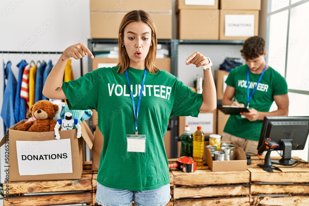 Young blonde girl wearing volunteer t shirt at donation stand pointing ...