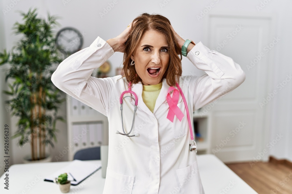 Middle age doctor woman wearing pink cancer ribbon on uniform crazy and ...