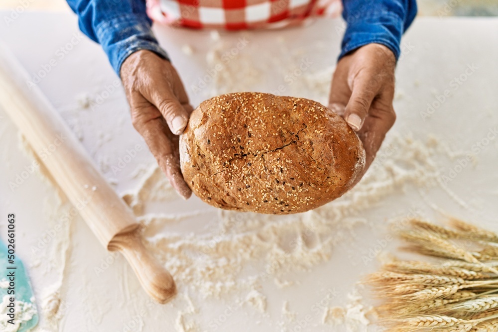 Senior man holding wholemeal bread at kitchen Stock Photo | Adobe Stock