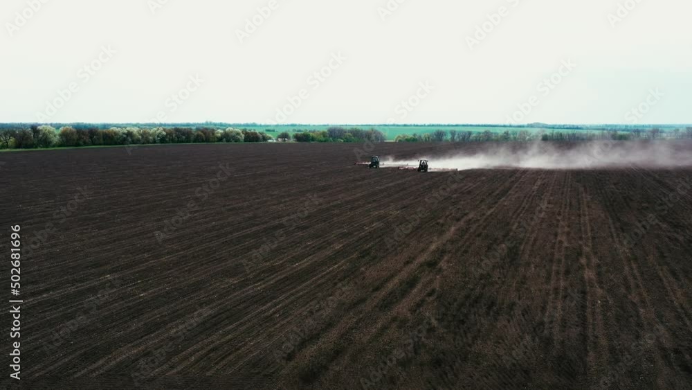 Top view on tractor ploughing dry and dusty farm field and preparing ...