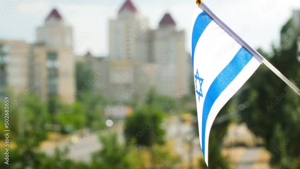National Flag of Israel set against blue sky and city street. Israeli ...