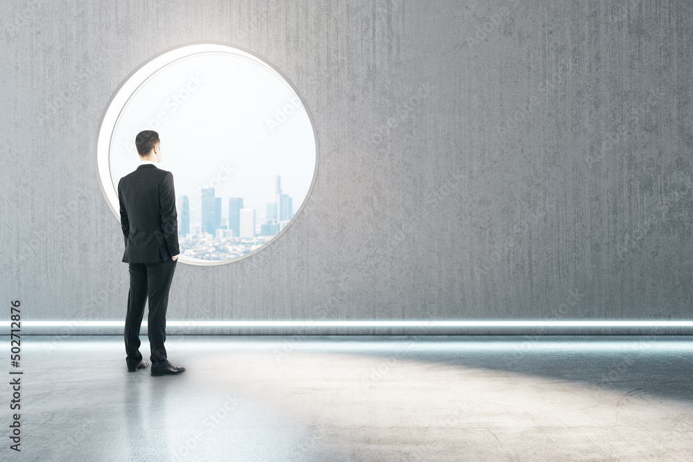Back view of thoughtful young man standing in creative modern concrete ...