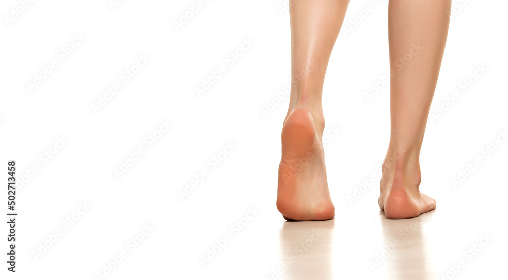Slender beautiful female bare feet rear view on a white background ...