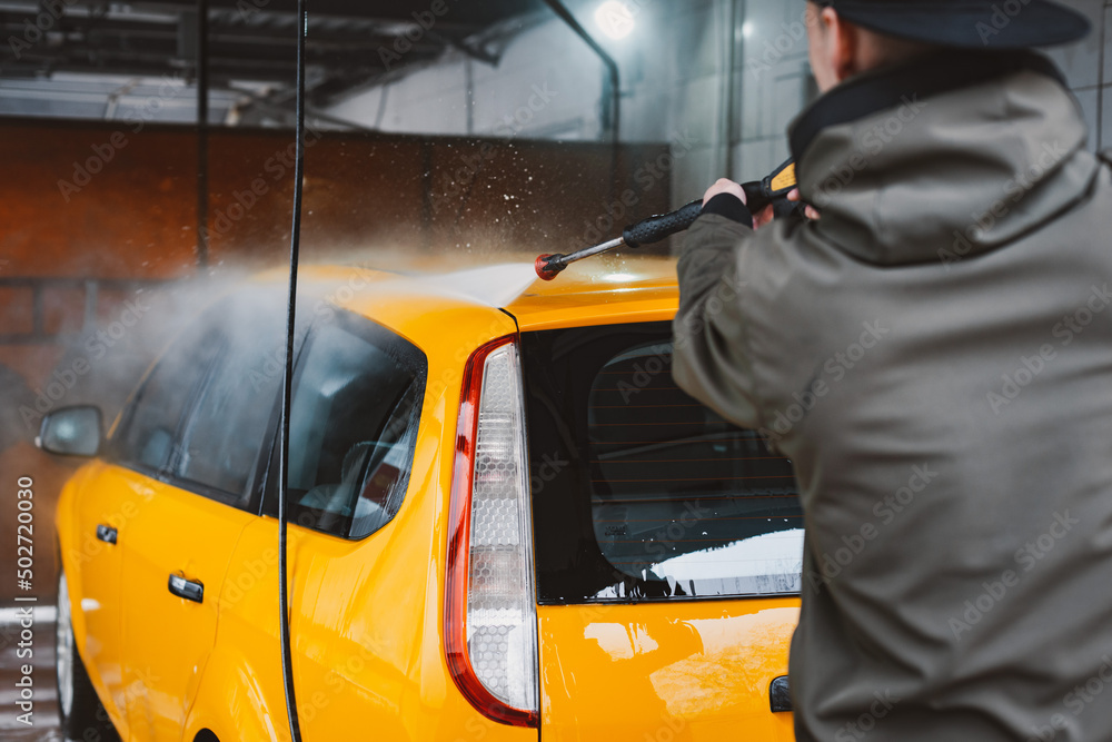 Washing a yellow car at a contactless self-service car wash. Washing a ...