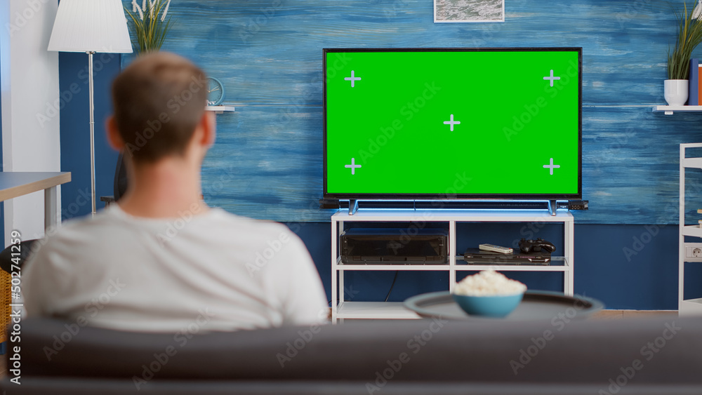 Man sitting on sofa looking at green screen on tv relaxing watching ...