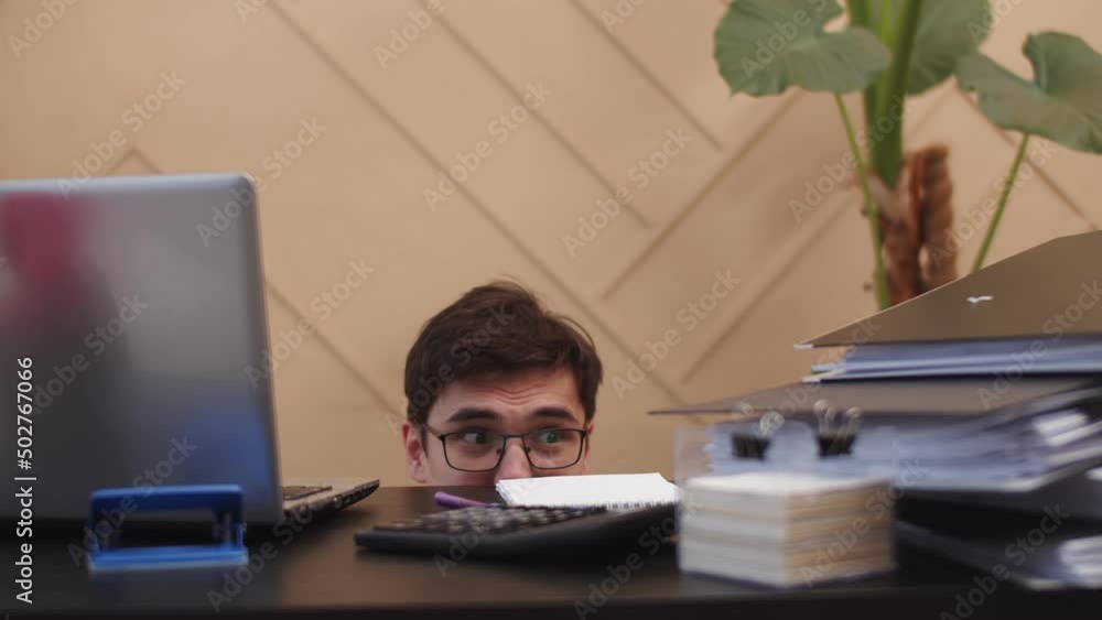 Office worker man with glasses, raises head from under table at work ...