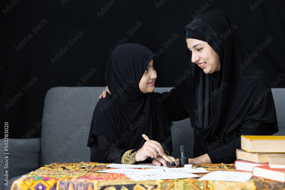 muslim mother with her daughter writing Arabic text with bamboo pens ...