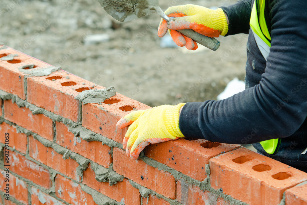 Bricklayer laying bricks on mortar on new residential house ...