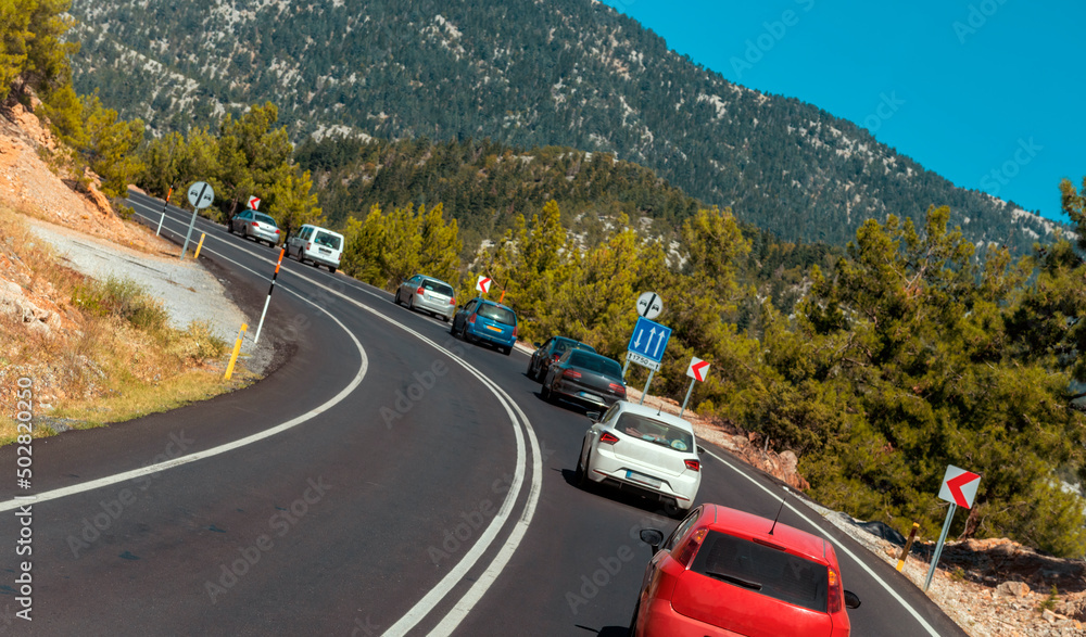 Cars moving in a row at the no overtaking zone in traffic. Paved road ...
