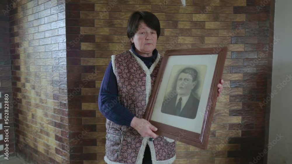 Senior 60s woman wipe old photo portrait of an ancestor.Adult female ...