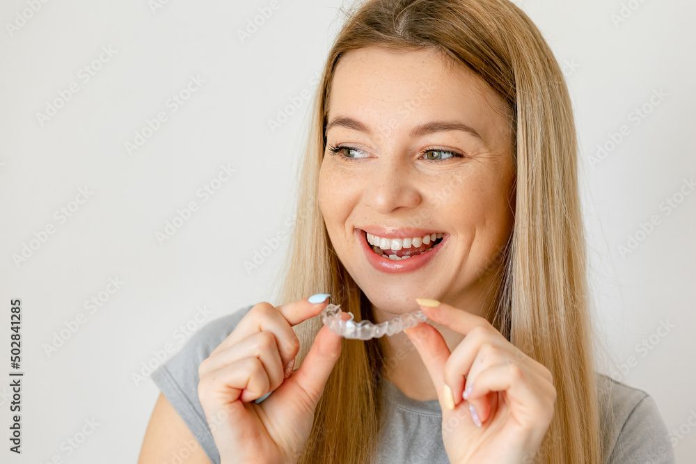 Beautiful cheerful woman is holding an invisalign bracer in a studio ...