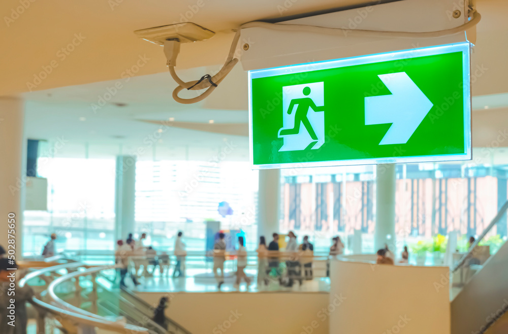 Focus at green electric emergency exit sign on ceiling with blurred ...