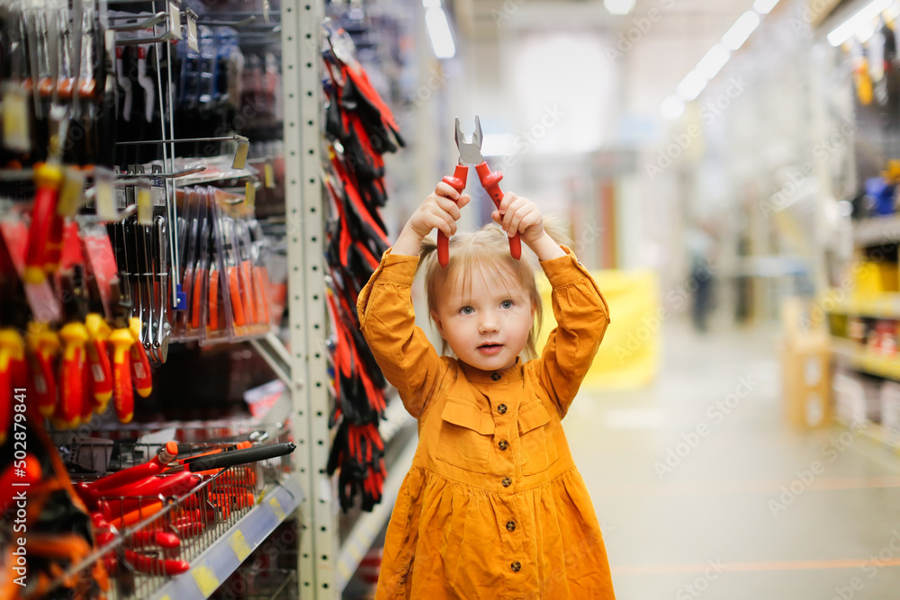 Foto de Cute girl child in mustard dress in hardware store, child plays ...