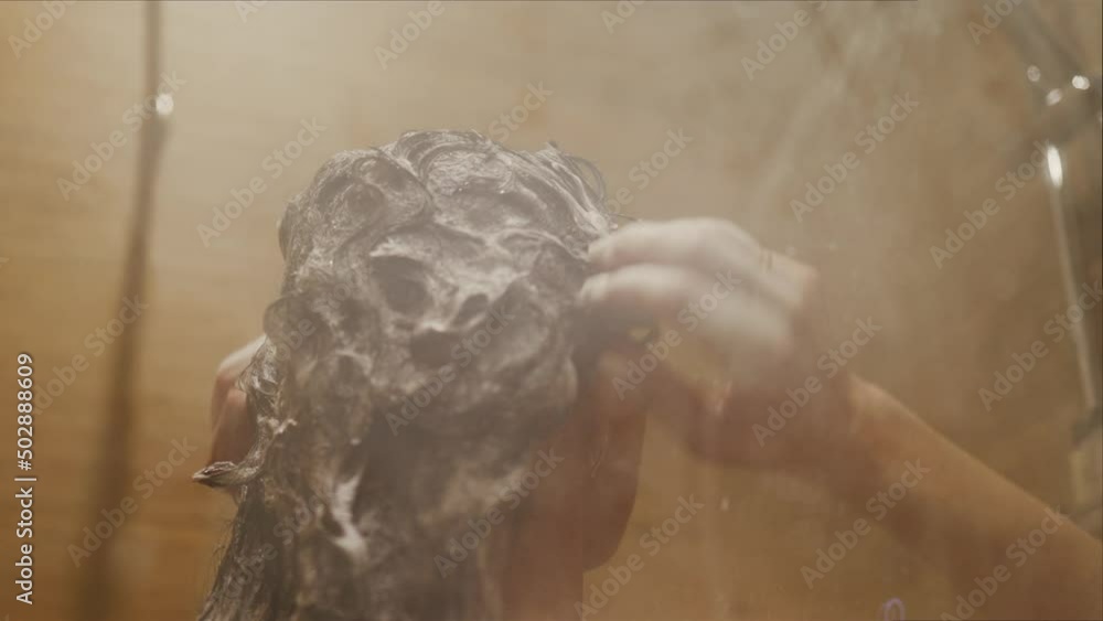 Woman Washing Her Hair. Back view of woman washing hair with shampoo ...