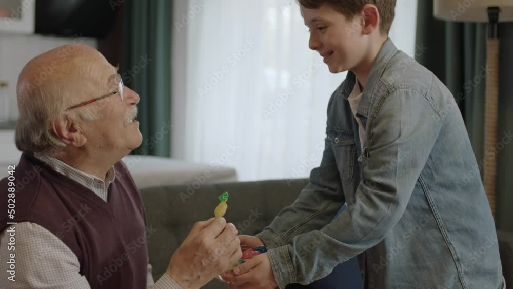Boy offering candy in bowl to his old grandfather.Little boy offering ...