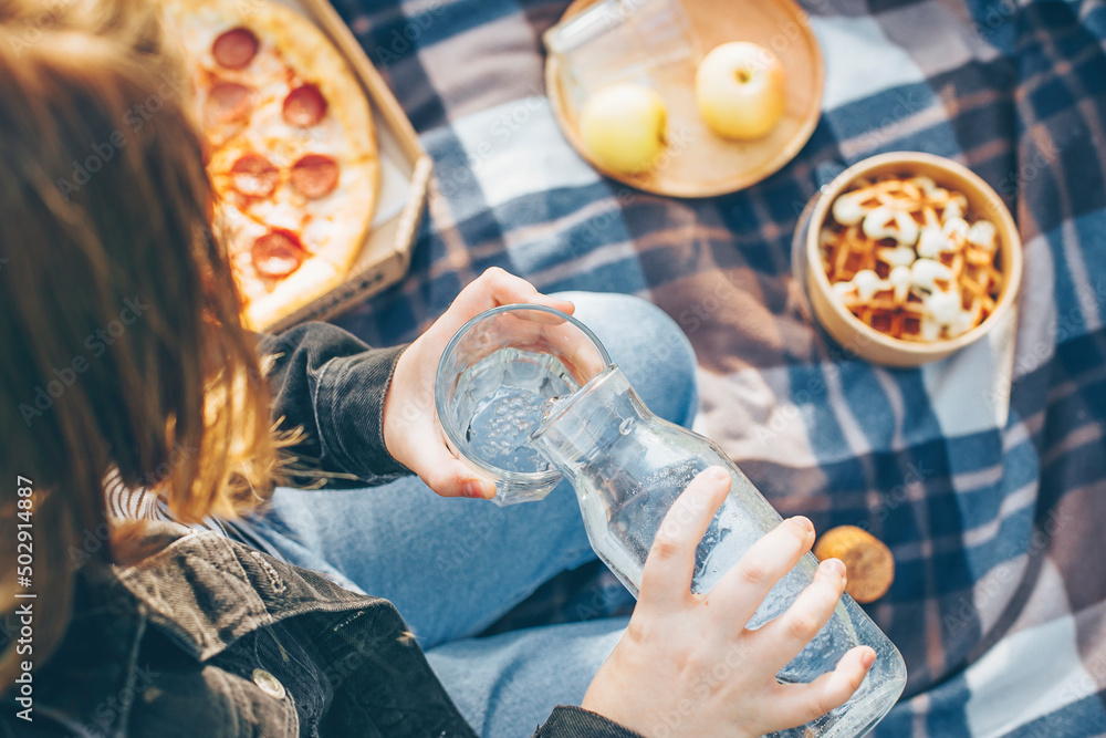 Girl pouring water into a glass while sitting in nature at a picnic Stock Photo | Adobe Stock