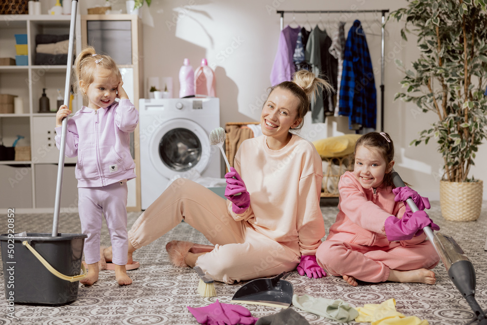 Happy family cleaning house together. Twin sisters helping mommy to ...