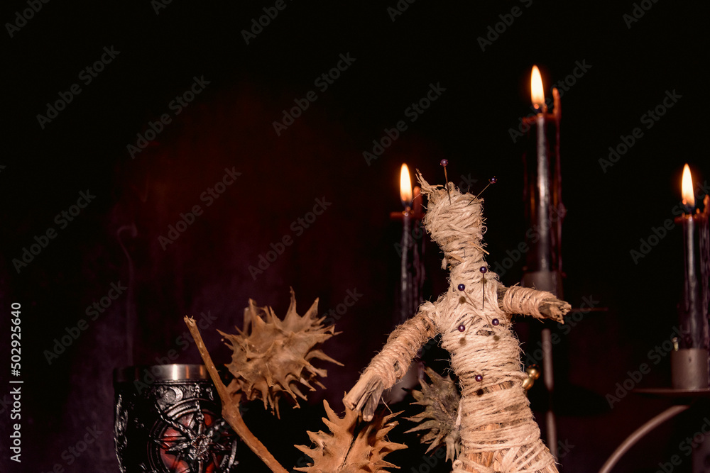 Voodoo doll, black candles, pentagram and old books on witch table ...
