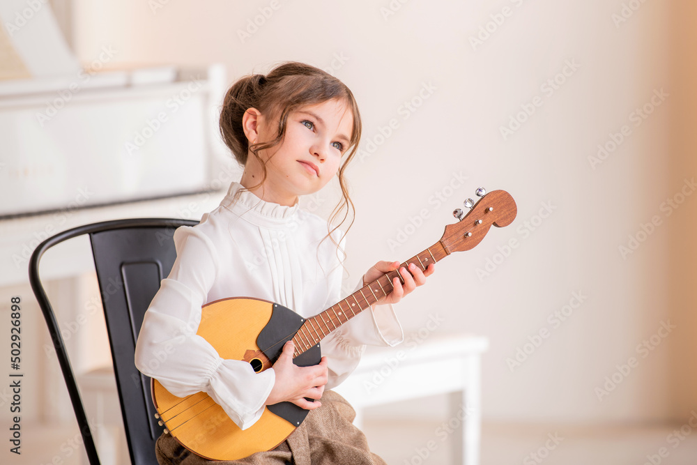A teenage girl a young musician plays a stringed musical instrument ...