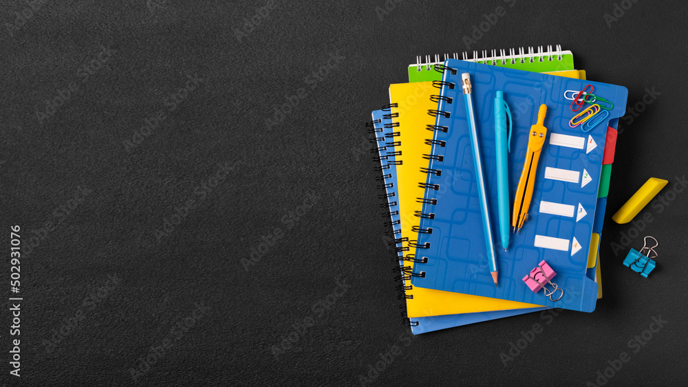 A stack of colored school notebooks and an alarm clock on a school ...