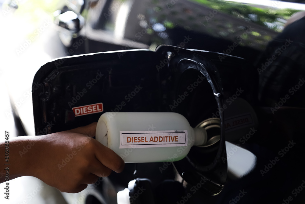 Male employee is adding diesel fuel additive to diesel tank. Increase ...