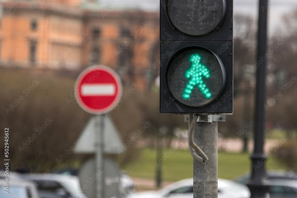 A traffic light for pedestrians with a symbol of a walking person is ...