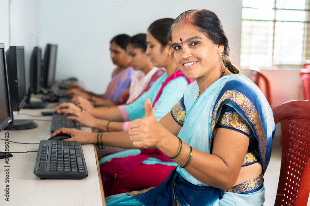 Smiling women showing thumbs up by looking camera during computer ...